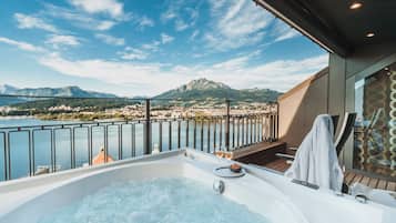 Banheira de hidromassagem com vista para um lago e montanhas.