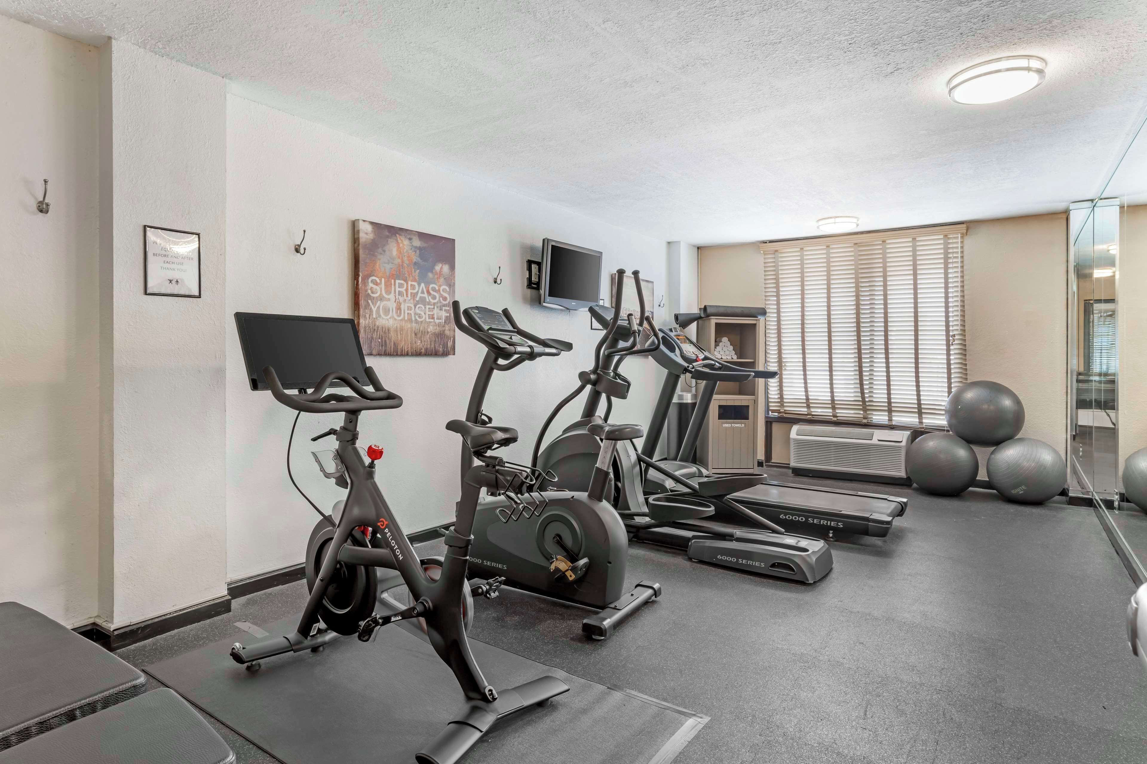 Uma academia com bicicletas ergométricas, esteiras e bolas de exercício.