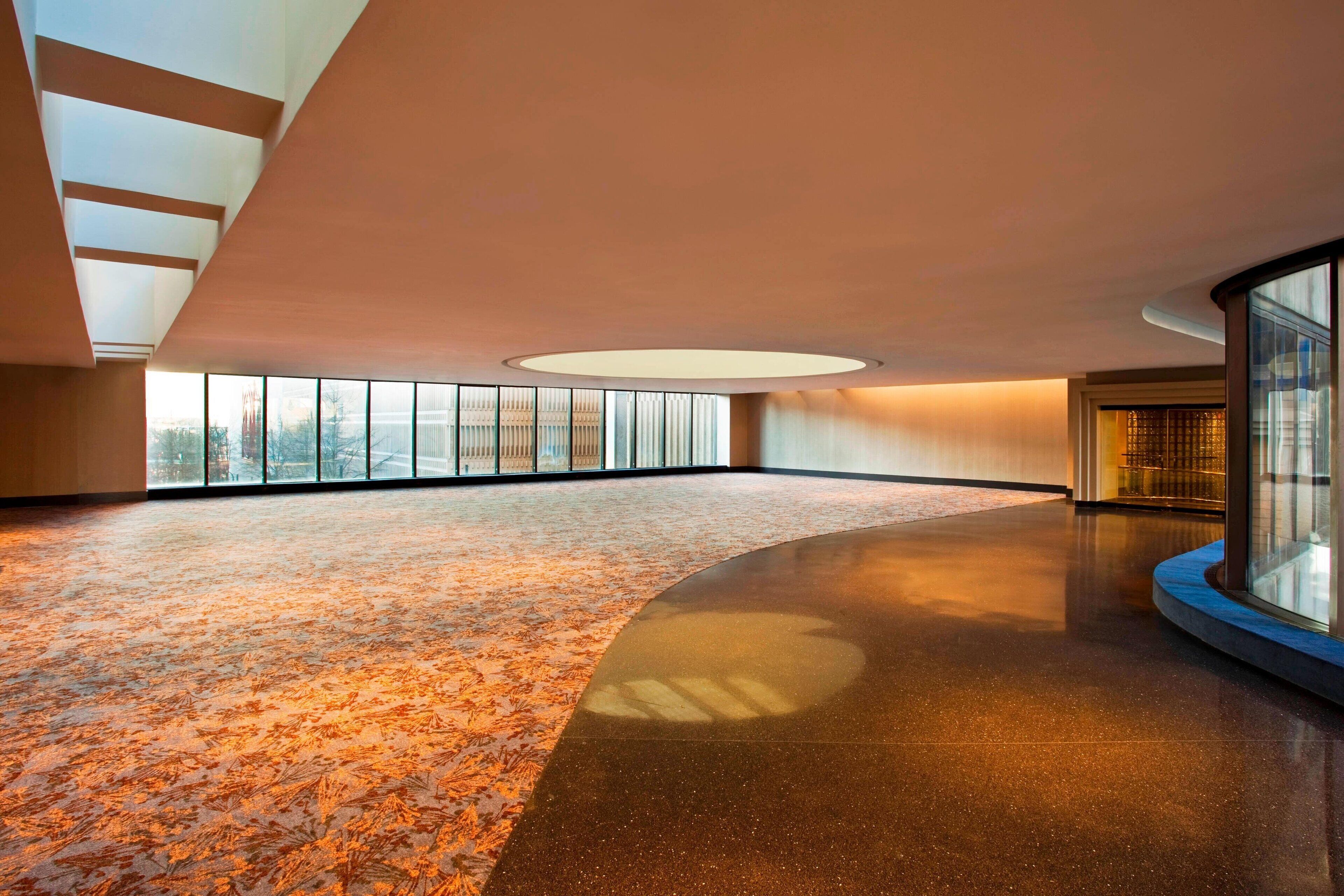 Um interior espaçoso, com grandes janelas, piso lustroso e pé direito alto.