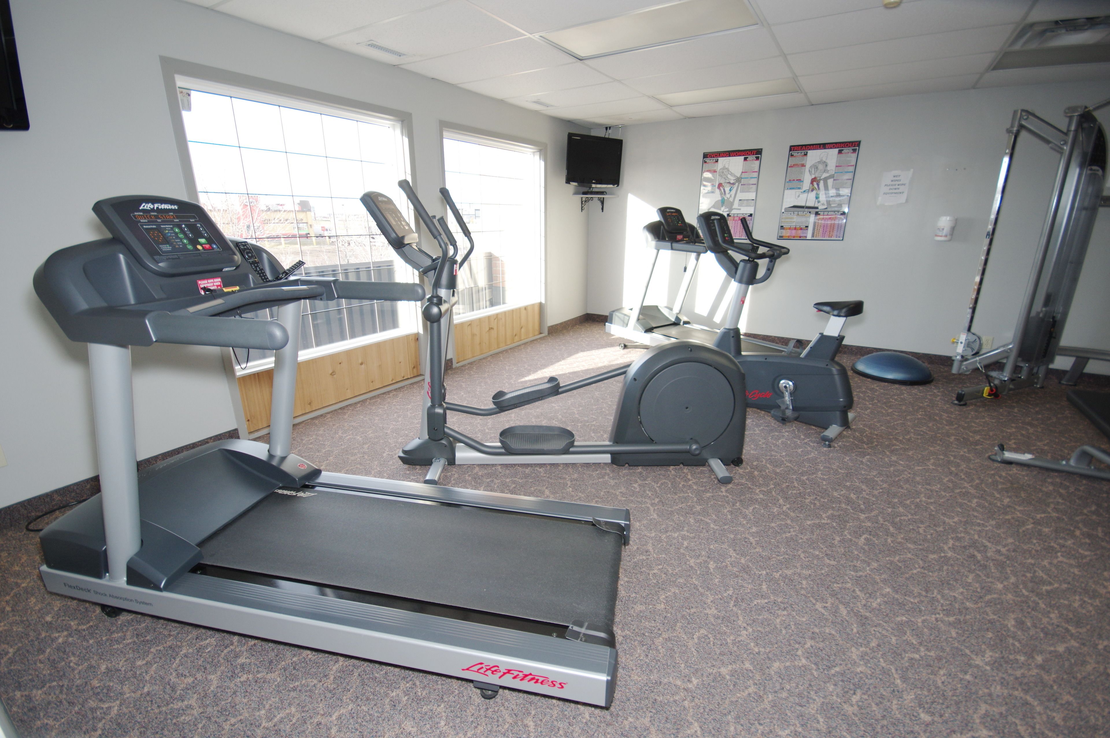 Centro de fitness com esteiras, bicicletas ergométricas e um aparelho de musculação.