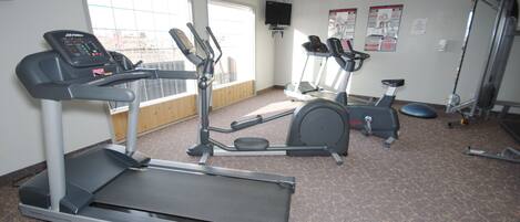 Centro de fitness com esteiras, bicicletas ergométricas e um aparelho de musculação.
