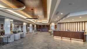 Um hall amplo com balcão de recepção, área de estar e design moderno no teto.