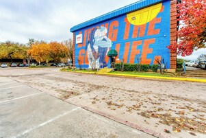Um edifício com um mural na lateral, um estacionamento e árvores de outono.