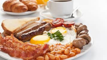 Prato de café da manhã com torradas, linguiça, bacon, ovos, feijão, cogumelos e tomates.