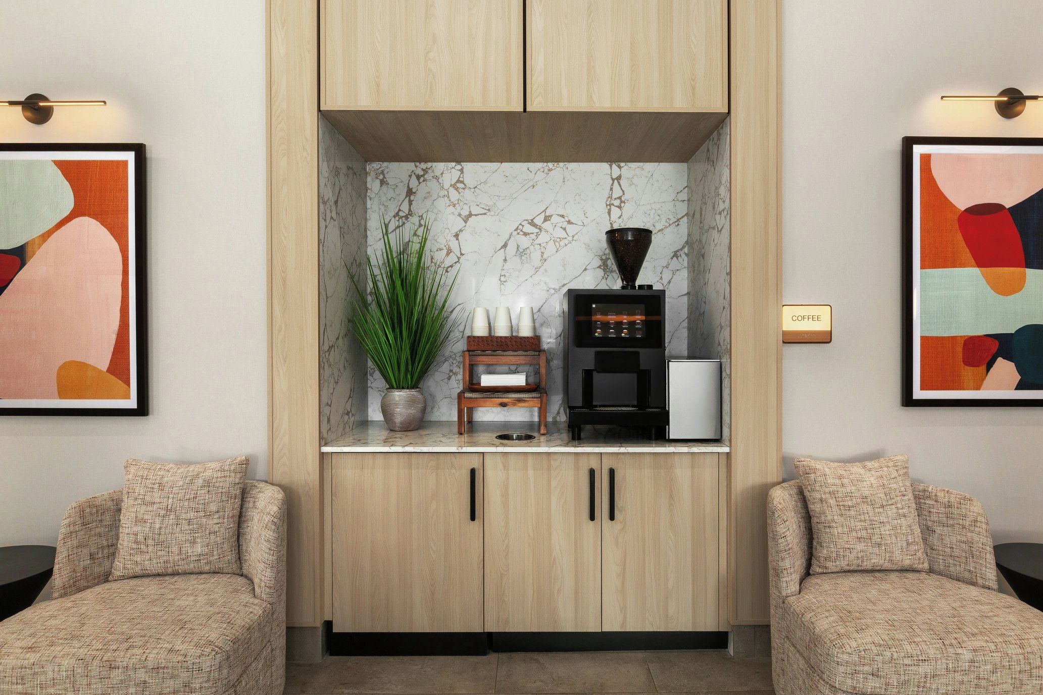 Cozinha moderna com máquina de café, uma planta e uma pequena mesa com xícaras.