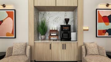 Cozinha moderna com máquina de café, uma planta e uma pequena mesa com xícaras.