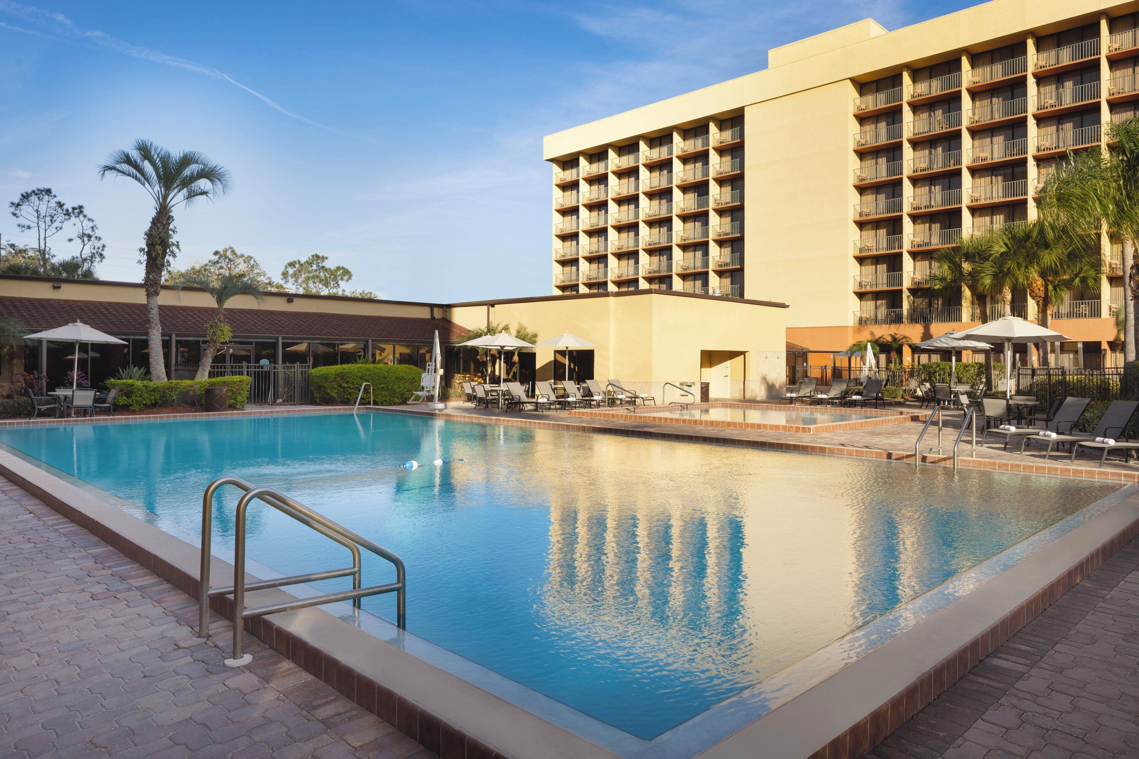 Um hotel com piscina, espreguiçadeiras e guarda-sóis.