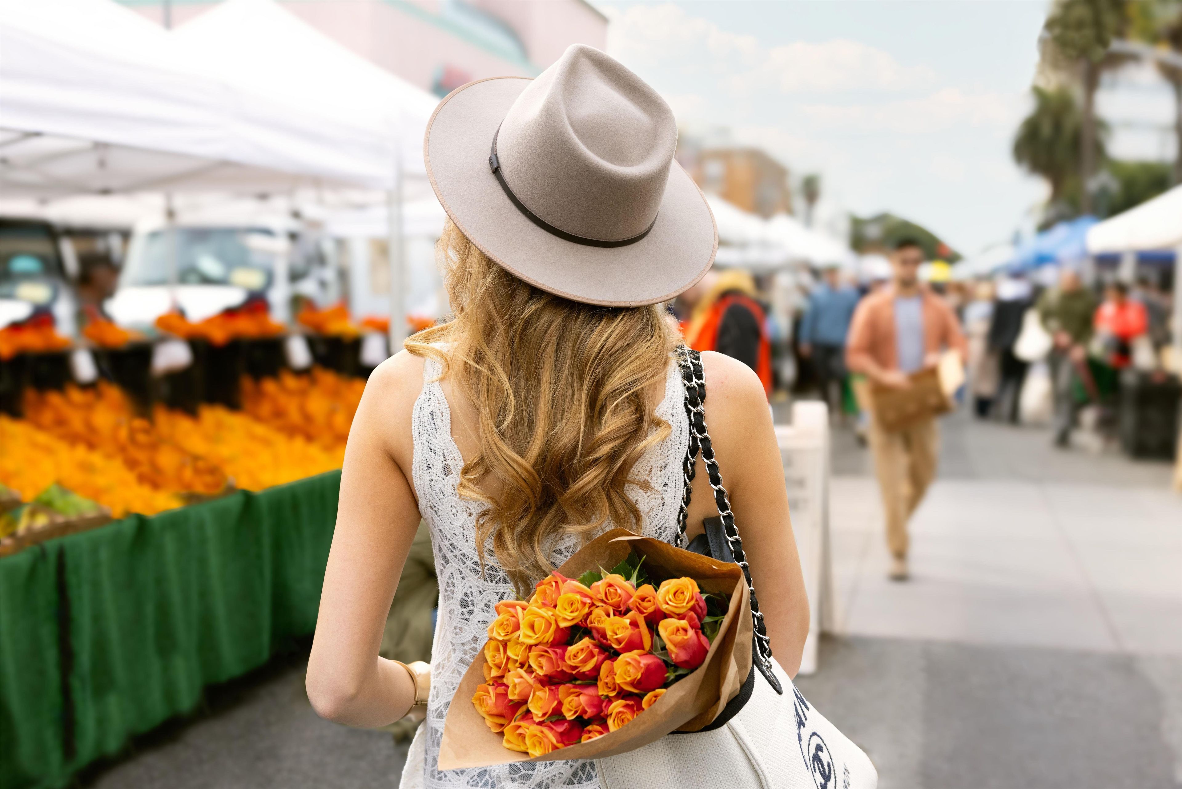 Uma pessoa segurando um buquê de flores em um mercado ao ar livre.