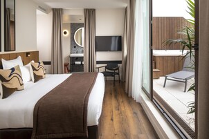 Quarto de hotel com uma cama grande, televisão, escrivaninha e vista para a piscina e área externa.