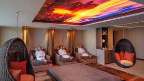 Uma sala de spa moderna com três cadeiras de massagem, um balanço e uma mesa para massagem.