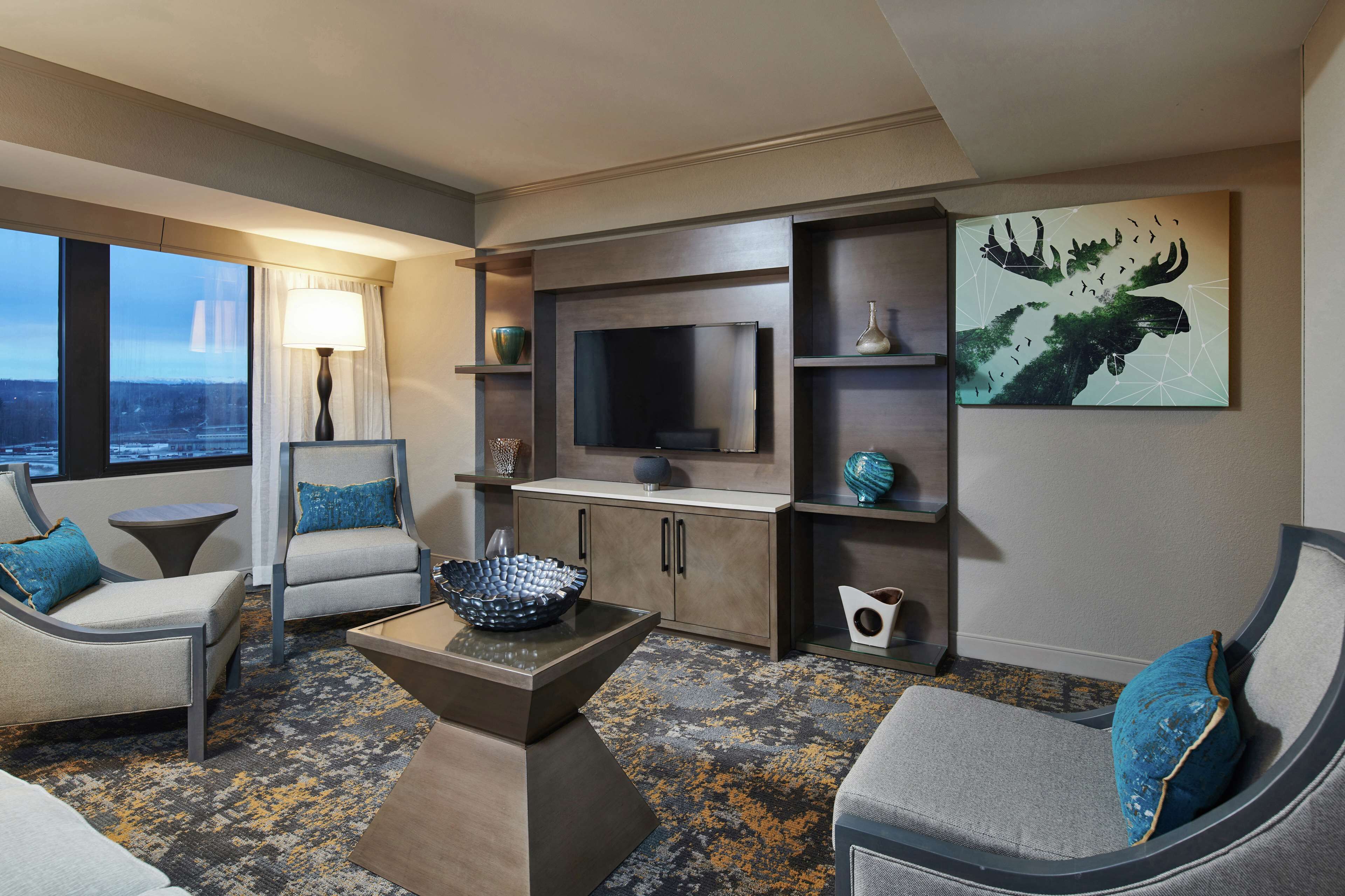 Quarto de hotel moderno com uma janela grande, televisão de tela plana, lareira e vista para a cidade.