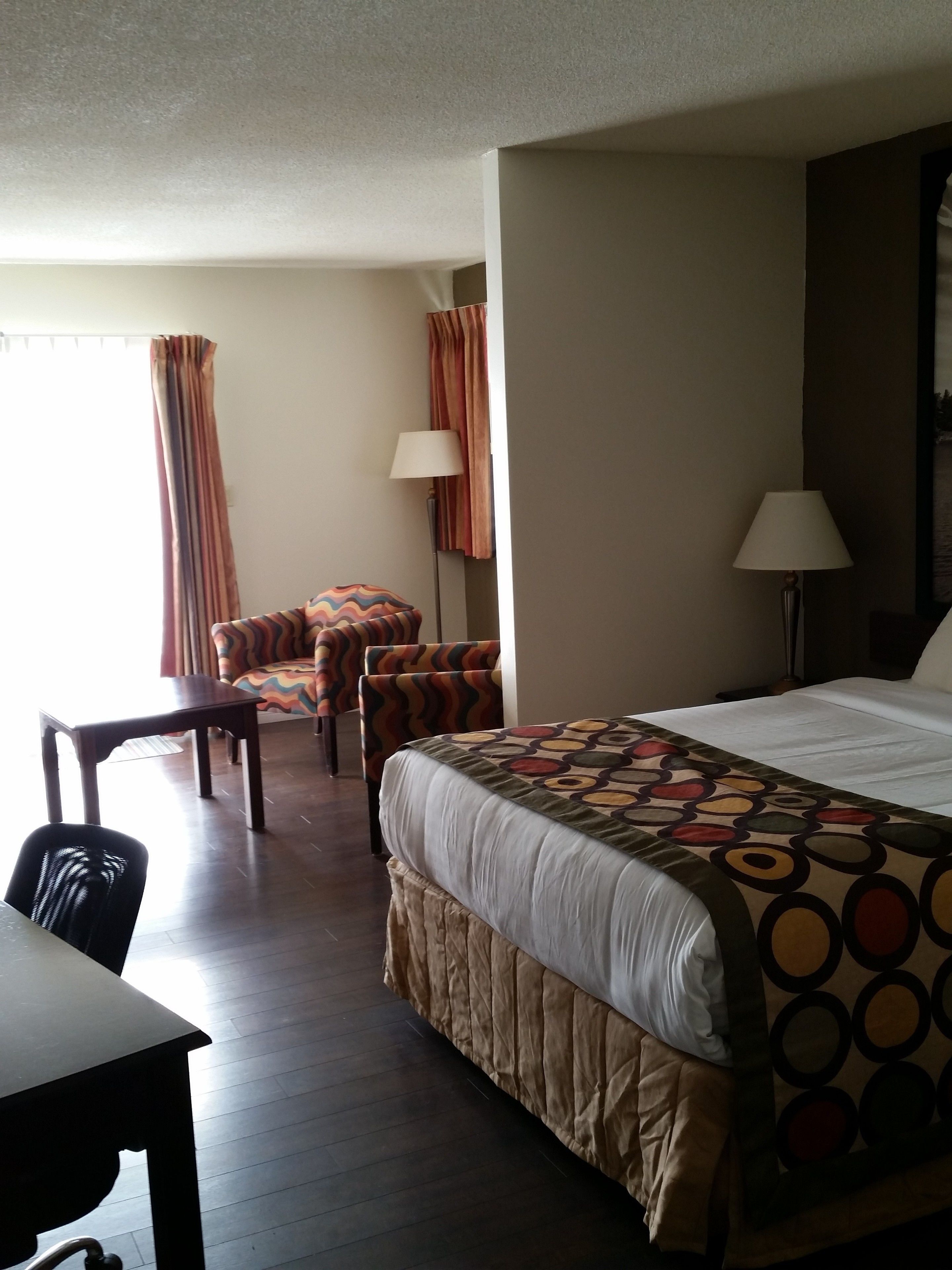 Quarto de hotel com cama, escrivaninha, cadeira e abajur.