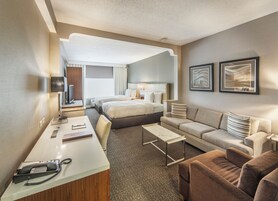 Quarto de hotel com cama, sofá, escrivaninha e televisão.