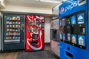 Uma área de máquinas de venda automática com máquinas Coca-Cola, Pepsi e um bebedouro.