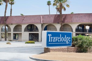 Edifício Travelodge com telhado de telhas vermelhas, várias arcos e uma placa.