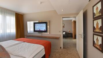Quarto de hotel com uma cama, televisão na parede e porta para um corredor.