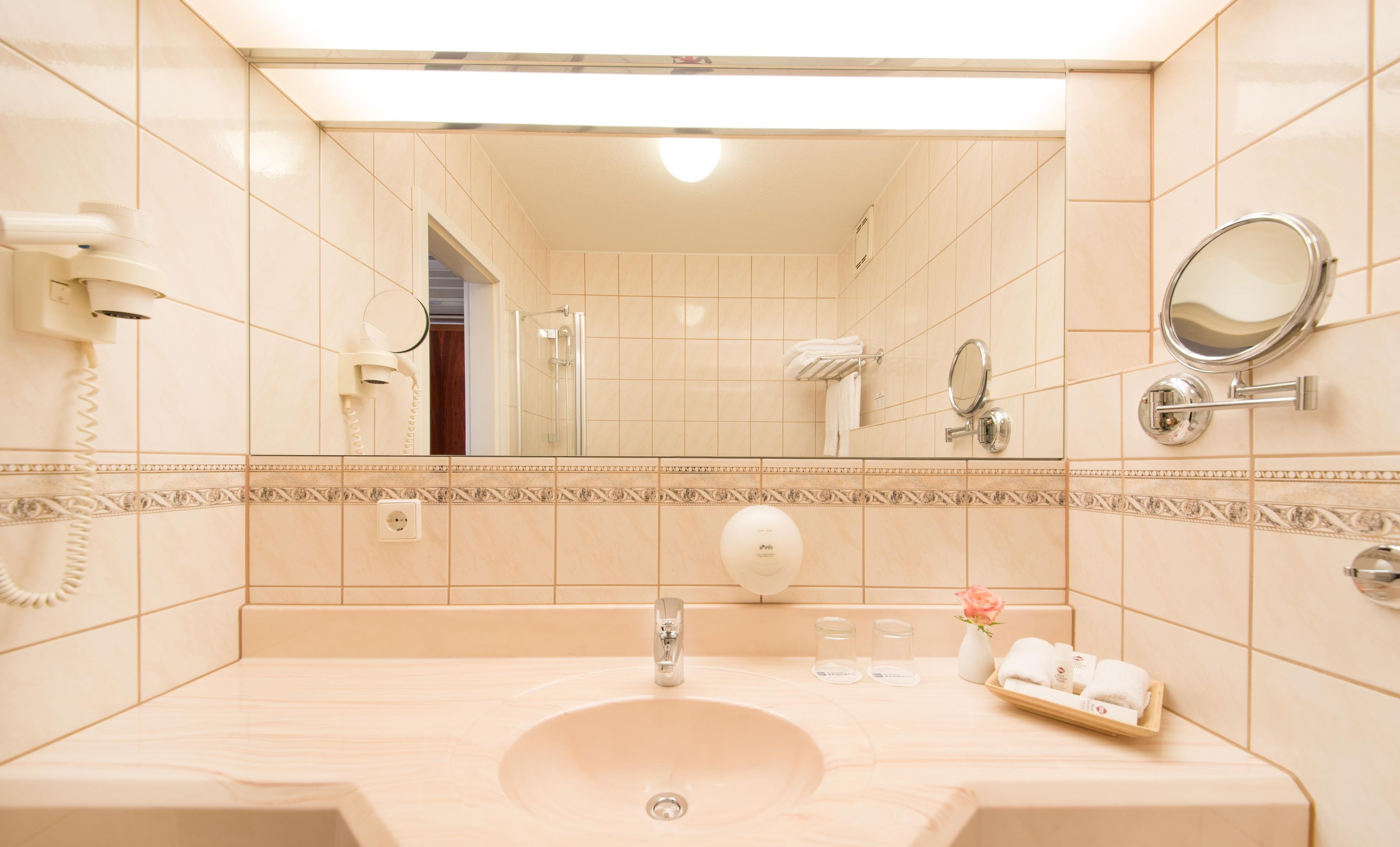 Casa de banho com lavatório, espelho, porta-toalhas e secador de cabelo.