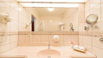 Casa de banho com lavatório, espelho, porta-toalhas e secador de cabelo.