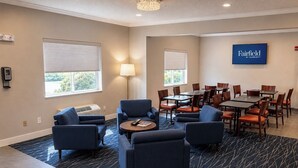 Um hall de hotel com áreas de estar, uma lareira e uma televisão exibindo o nome do hotel.