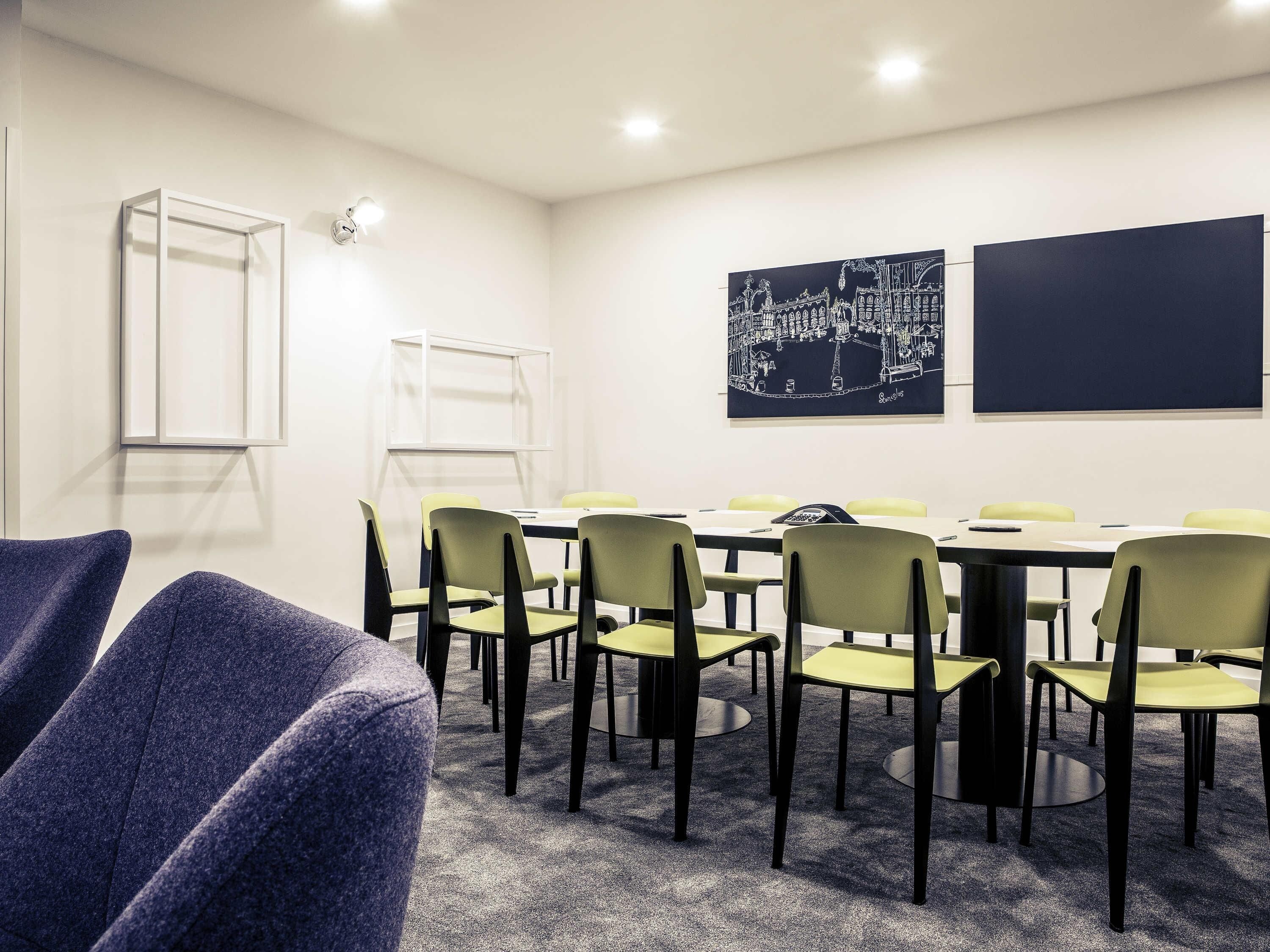 Uma sala de conferência com quadro branco, tela de projetor e uma grande obra de arte na parede.