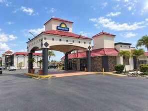 Entrada de um hotel Days Inn com telhado de telhas vermelhas, estacionamento e céu claro.