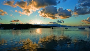 Um lago tranquilo ao pôr do sol, com barcos e uma linha de costa distante.
