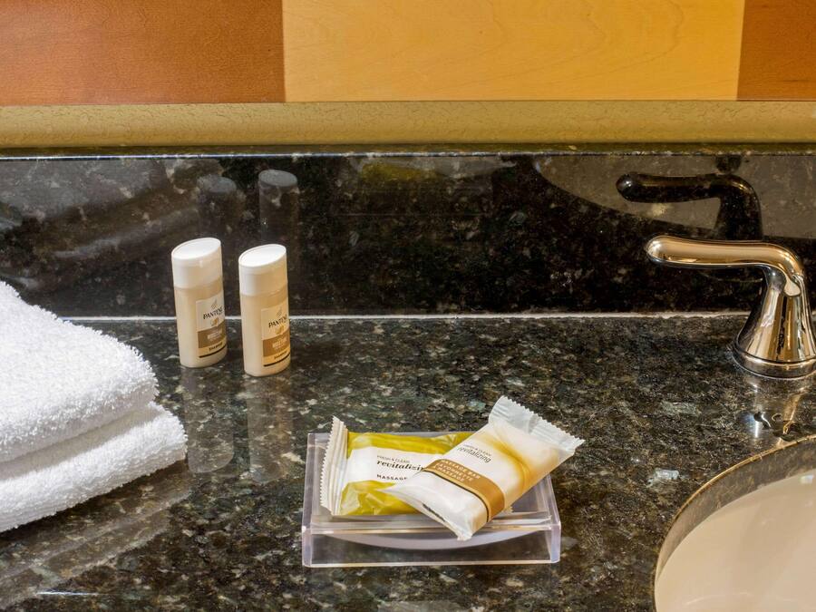 Uma bancada de banheiro com toalha, duas embalagens de creme para as mãos e um tubo de loção.
