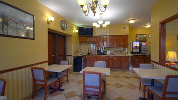 Uma sala de jantar com cadeiras e mesas de madeira, uma cozinha com armários de madeira e um candelabro.