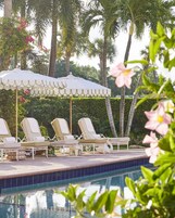 Uma área à beira da piscina com espreguiçadeiras e um toldo.