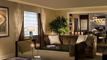 Quarto de hotel bem equipado, com sofá, área de jantar e uma grande planta.