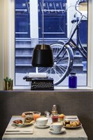 Mesa de café da manhã com máquina de escrever, bicicleta e vista pela janela.