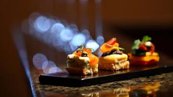Uma mesa de sobremesas com vários pratos pequenos, um copo de vinho tinto e um fundo desfocado com luzes bokeh.