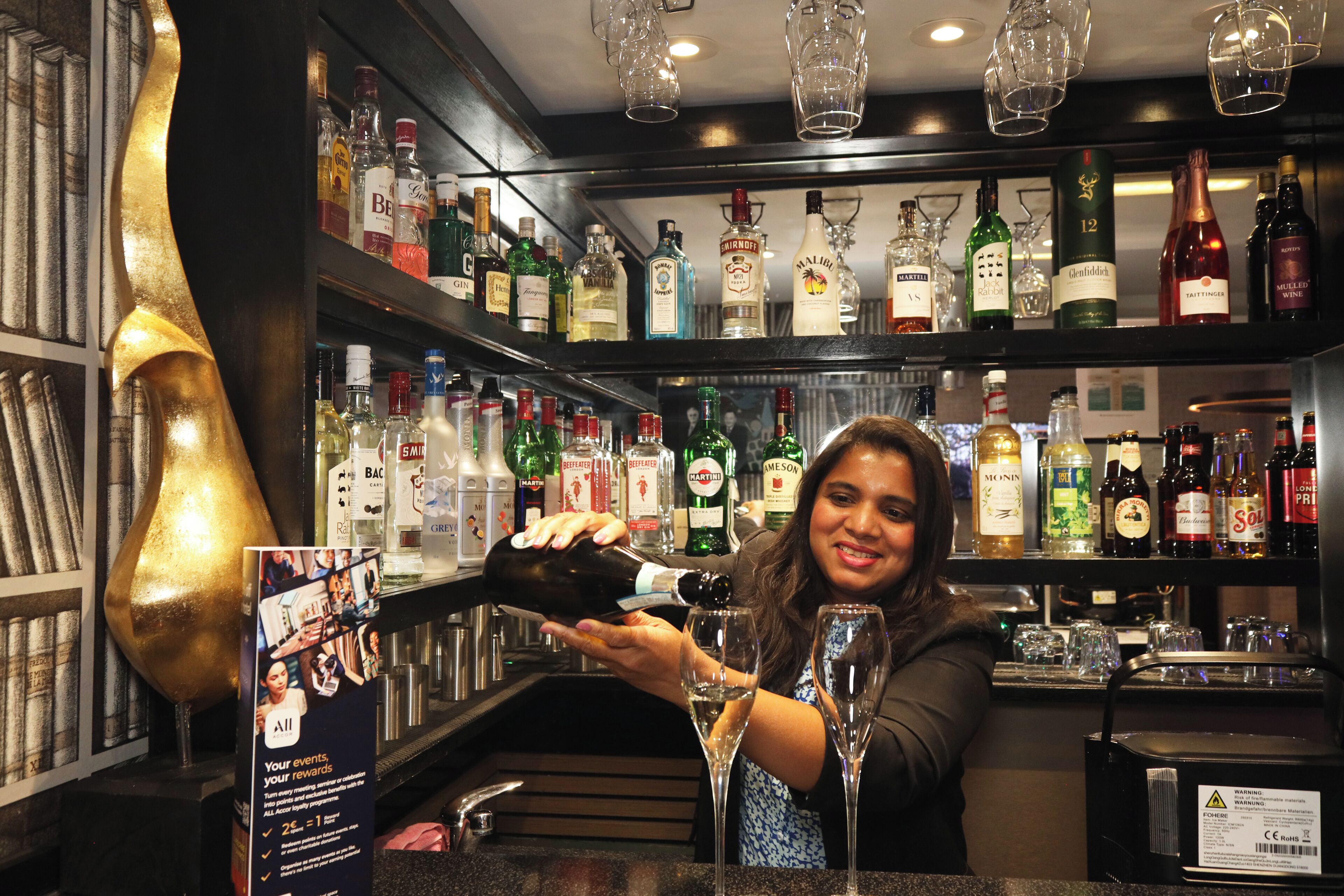 Uma  área de bar com diversas garrafas de bebidas e copos.