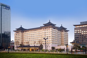 Um hotel com vários andares e elementos arquitetônicos chineses tradicionais, como telhados curvos e um pátio central.