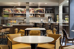 Um restaurante moderno com área de bar, arranjos de assento e cardápio exposto.