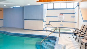 Uma piscina interna com chão de azulejo, uma banheira de hidromassagem e um aviso na parede.
