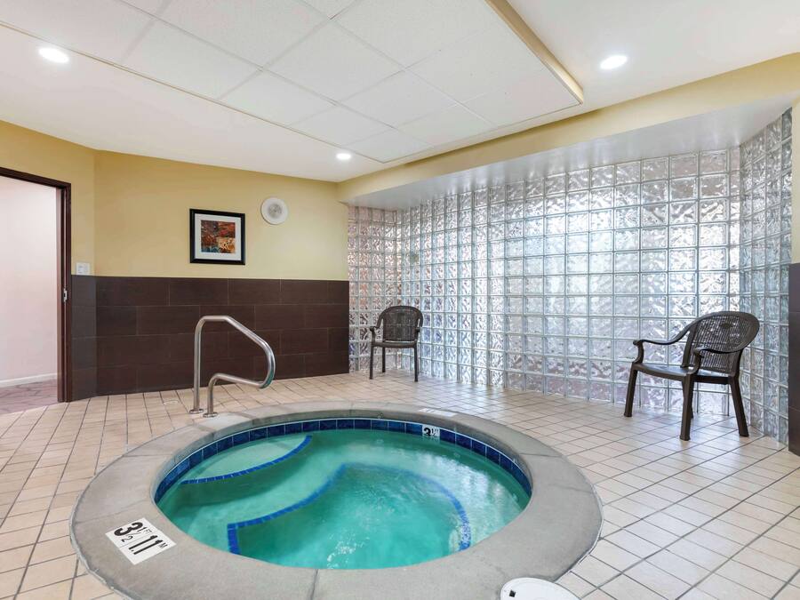 Piscina com chão em mosaico e uma cadeira perto.