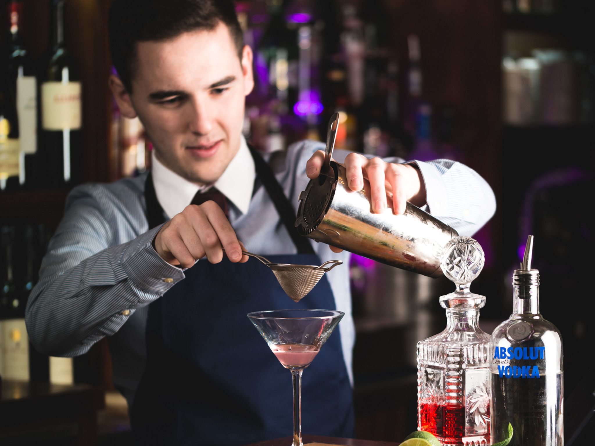 Um bartender a servir uma bebida num copo de martini.