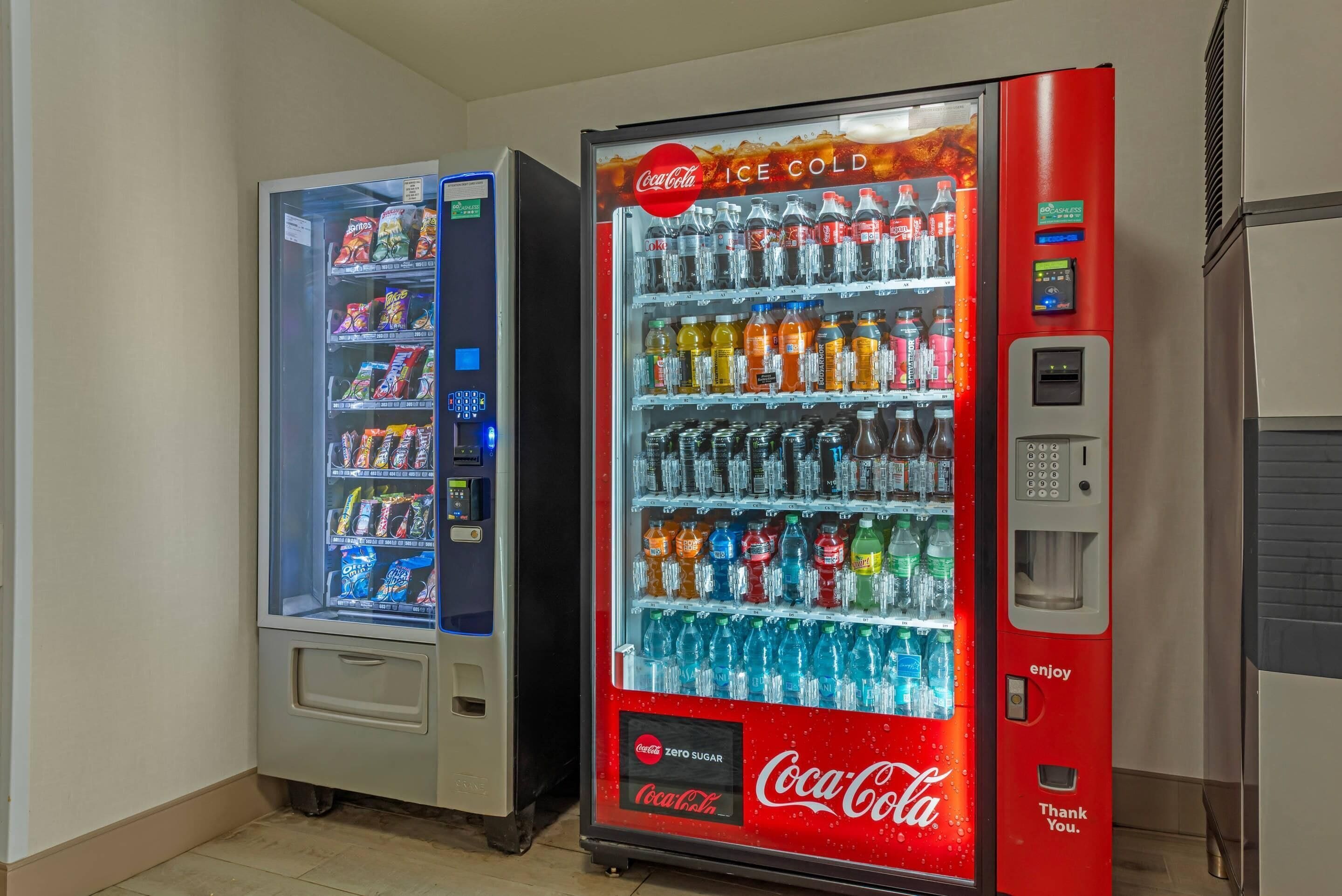 Duas máquinas de venda automática, uma com o logotipo da Coca-Cola e outra com opção de 60% menos açúcar.