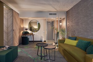 Uma sala de estar moderna com um sofá, duas mesas redondas, uma mesa de centro e uma planta decorativa.