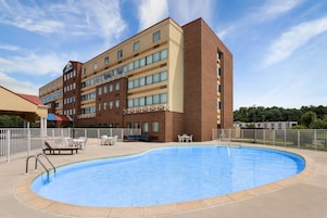 Hotel com piscina, área de estar ao ar livre e fachada de tijolos.