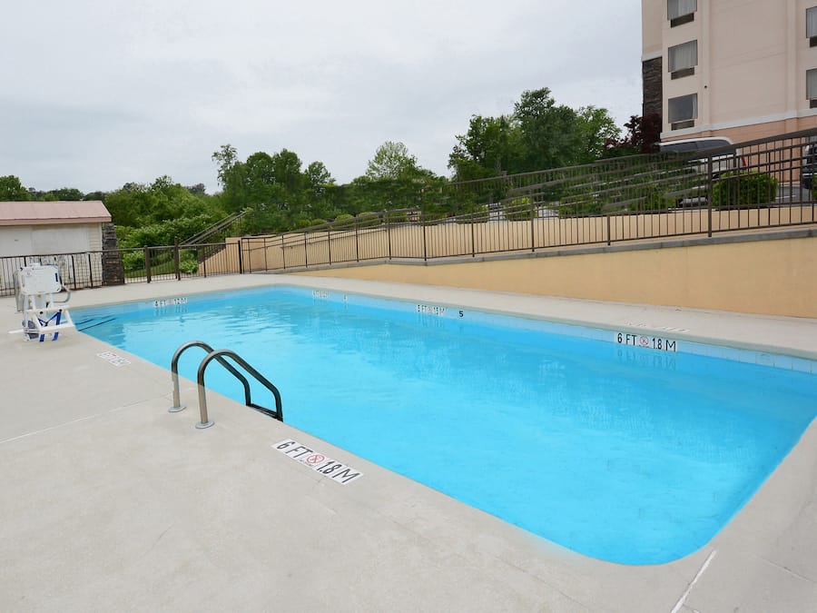 Piscina retangular com escada de metal e cadeira do salva-vidas.