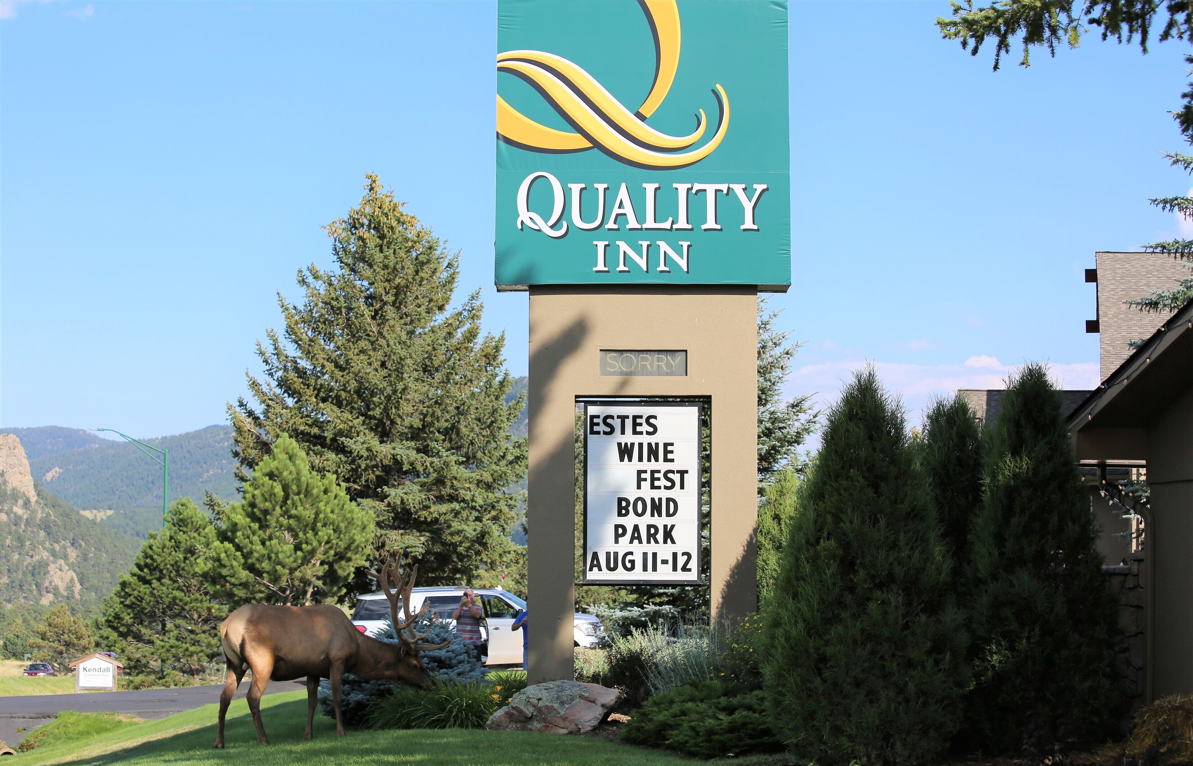 Placa da Quality Inn com uma placa de 'Desculpe' embaixo e um aviso para o Estes Wine Fest no Bond Park de 11 a 12 de agosto.