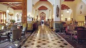 Um hall imponente com piso xadrez, alto teto de madeira e lustres elaborados.
