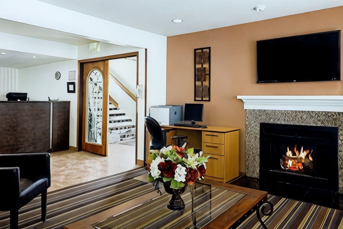 Quarto de hotel com lareira, televisão de tela plana, escrivaninha e uma cadeira.