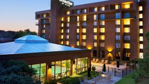 Um hotel com piscina no terraço, várias varandas e fachada bem iluminada.