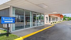 Entrada de um hotel Travelodge, com placa visível, portas de vidro e área de estacionamento coberta.