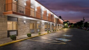 Um hotel com fachada de pedra, várias varandas e um estacionamento com vagas para deficientes.