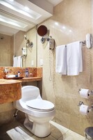 Um banheiro moderno com toucador de mármore, vaso sanitário, espelho e porta-toalhas.