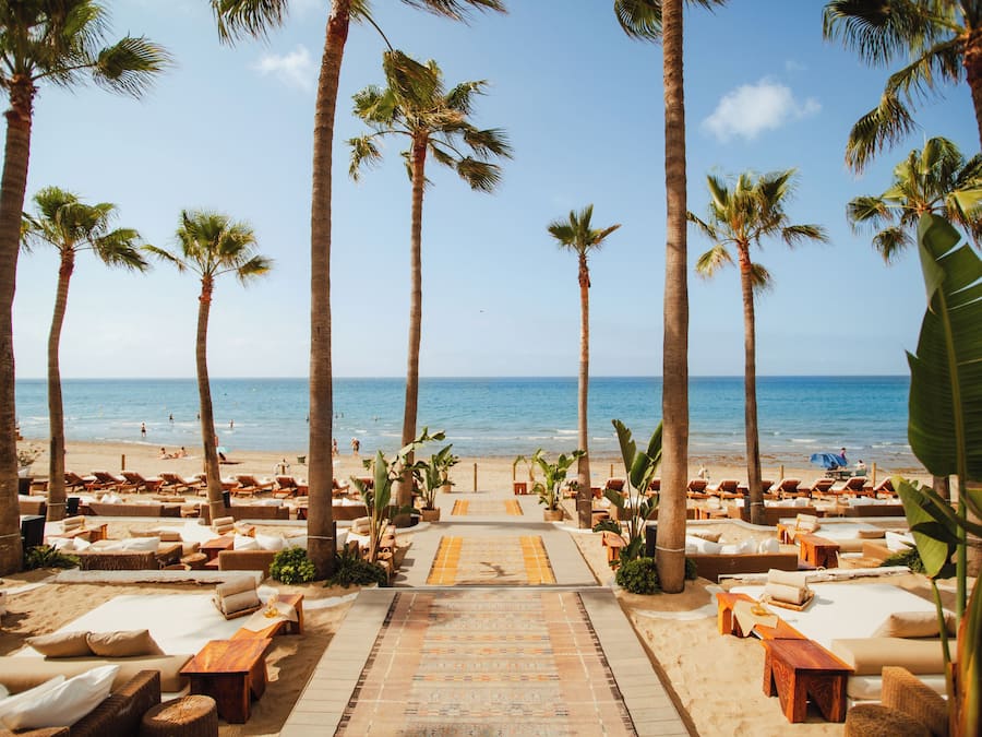 Na praia, espreguiçadeiras, guarda-sóis, toalhas de praia